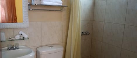 Casa de banho com sanita, lavatório e prateleira com artigos de higiene pessoal.