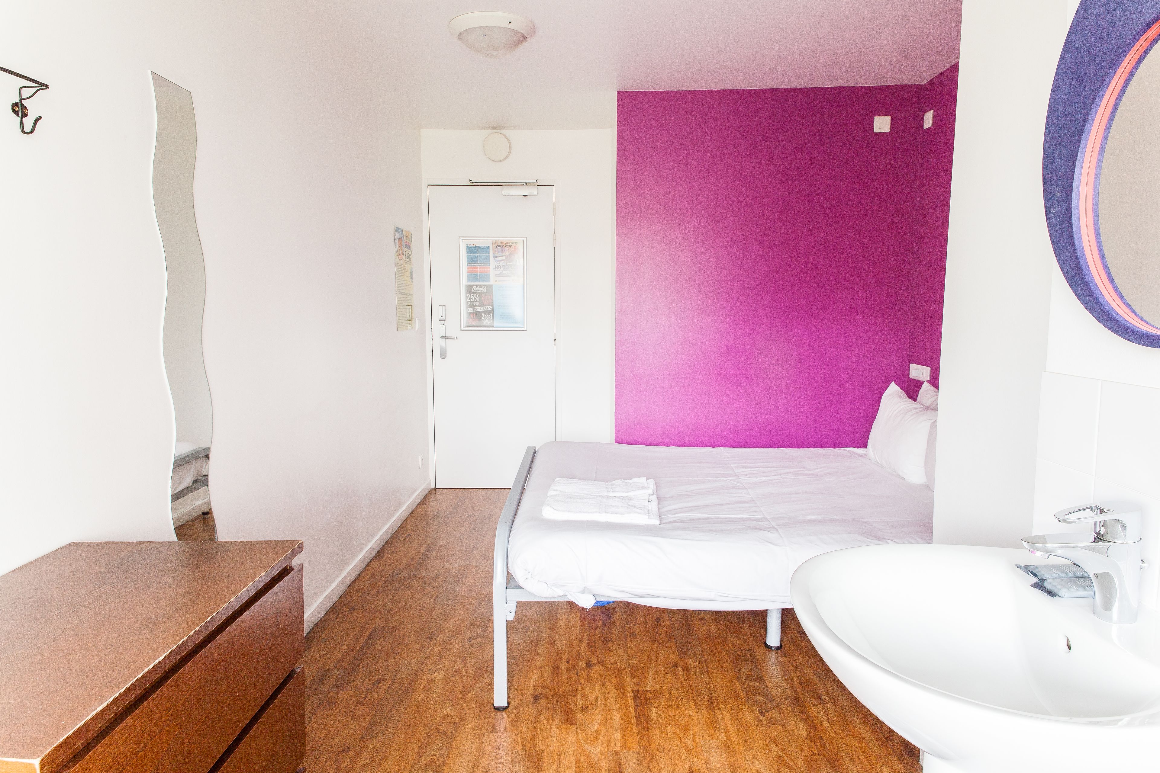 Quarto com cama, mesa de cabeceira, pia branca e espelho.