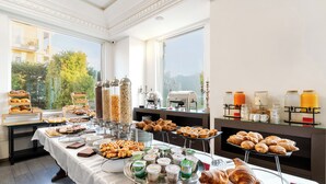 Buffet com diversos alimentos e bebidas, incluindo doces, frutas e laticínios.