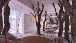 Interior moderno com área de estar central, rodeada por elementos em madeira natural e uma luminária suspensa.