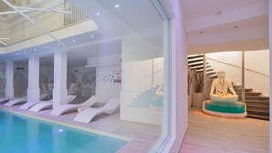 Piscina interior moderna com espreguiçadeiras e uma estátua.