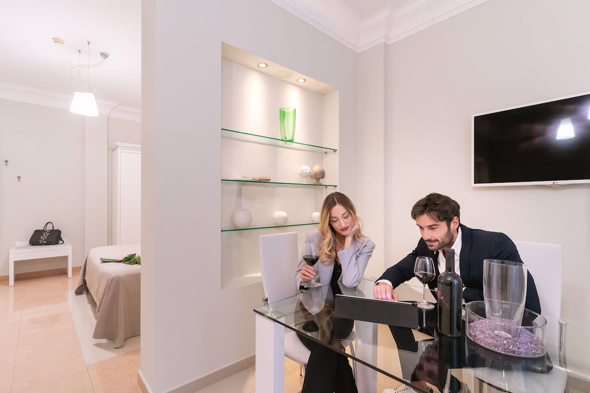 Quarto de hotel moderno com mesa de vidro, televisão de tela plana e decoração minimalista.