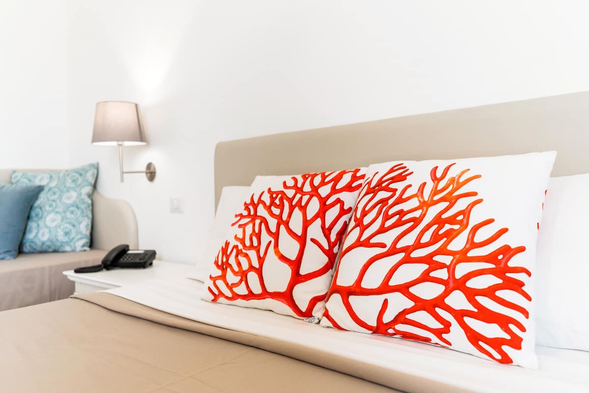 Quarto de hotel com uma cama, mesa de cabeceira, abajur e telefone.