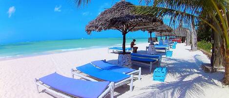 Na praia, areia branca, guarda-sóis