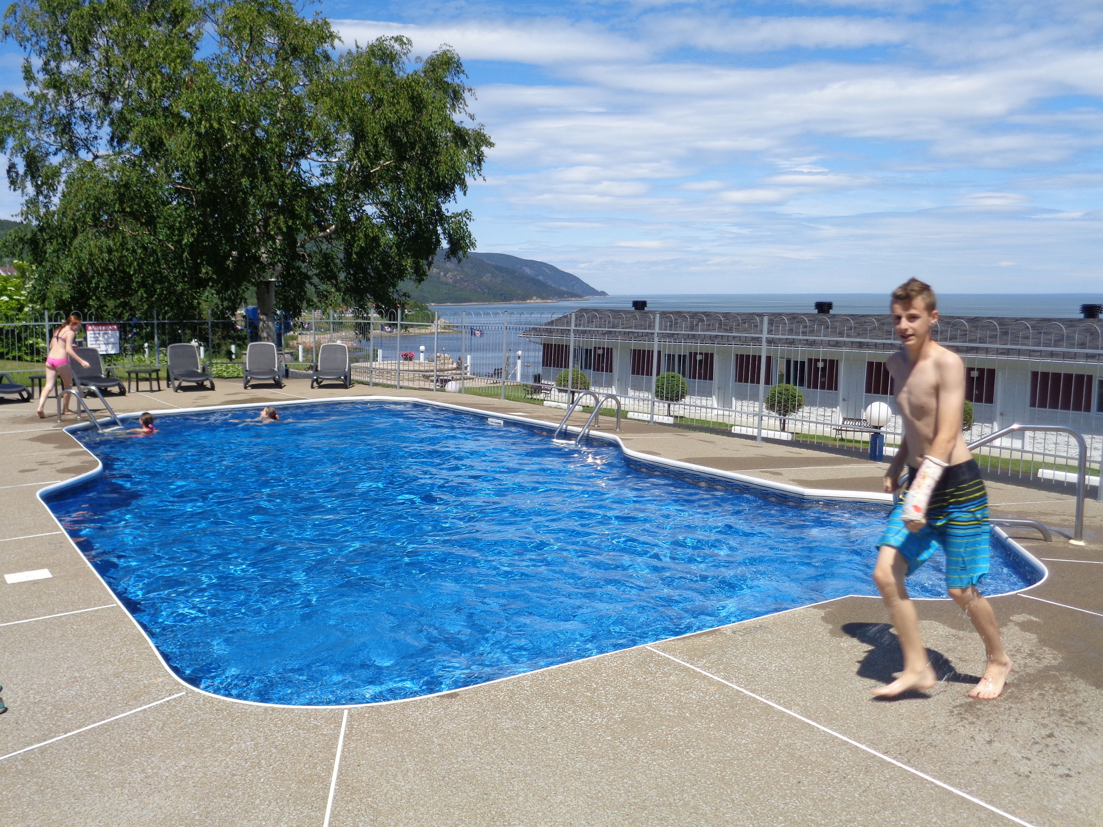 Piscina com vista para o oceano e um edifício ao fundo.