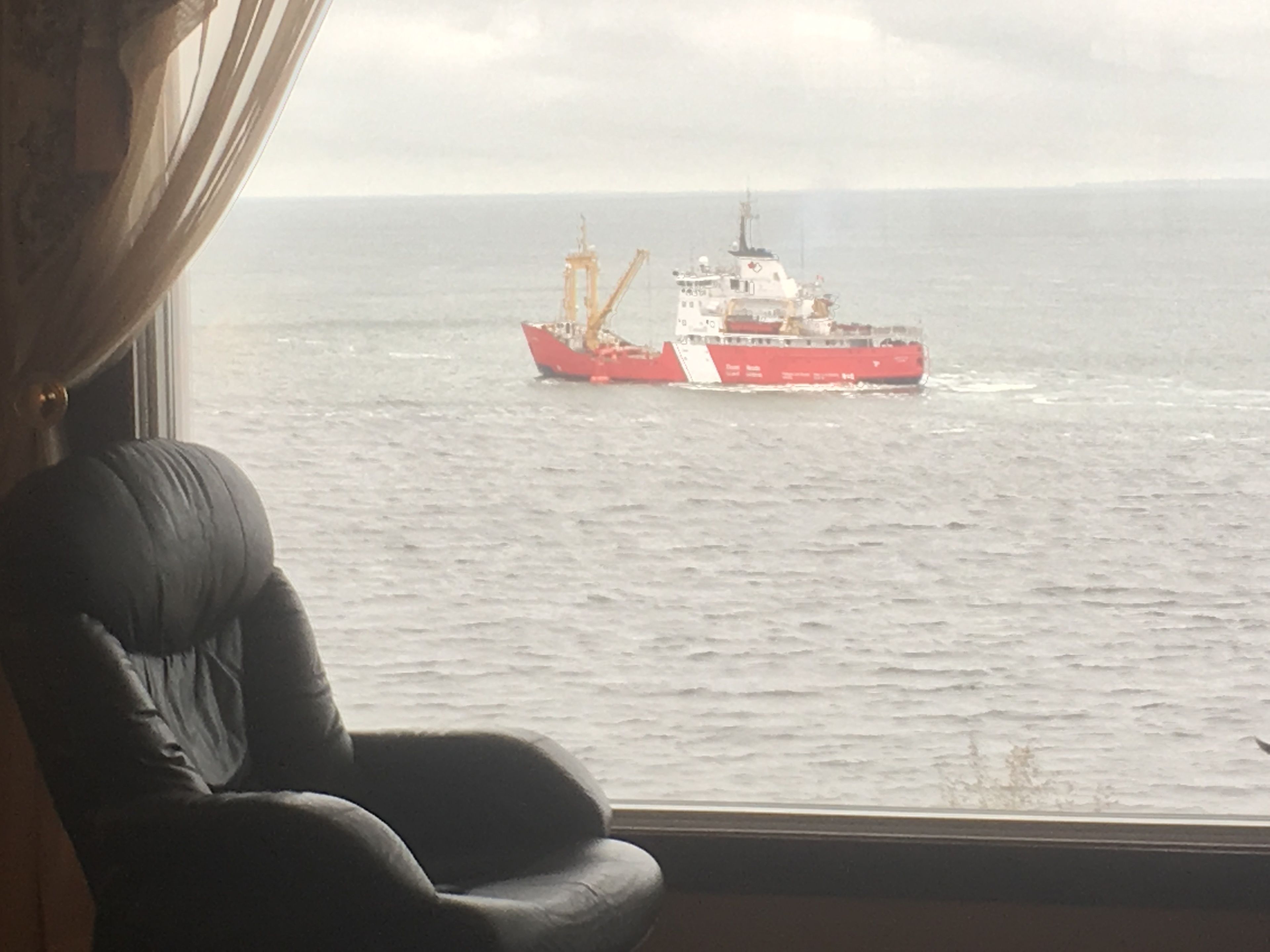 Vista do mar através de uma janela, com uma cadeira em primeiro plano.