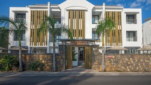 Um hotel moderno com fachada de pedra, janelas amplas e uma placa com a inscrição "GDSUN Beach Hotel".