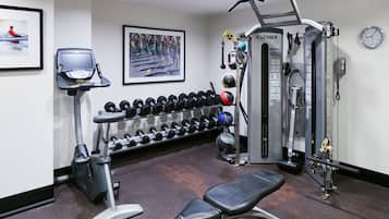 Uma academia com equipamentos de ginástica, halteres e esteira.