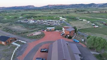 Um amplo parque de casas motorizadas, com várias unidades estacionadas em áreas designadas, rodeado por campos abertos e montanhas ao longe.