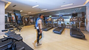 Academia moderna com esteiras, aparelhos de musculação e uma parede de vidro com vista.