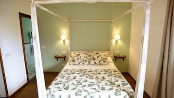 Uma cama de dossel com roupa de cama florida, duas luminárias de cabeceira e piso de madeira.