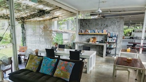 Um quarto espaçoso com um sofá preto, uma mesa de jantar e uma estante de livros.