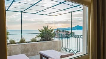 Varanda com vista para o mar e montanhas, com pérgola, área de estar e plantas em vasos.