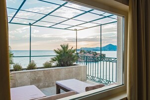 Varanda com vista para o mar e montanhas, com pérgola, área de estar e plantas em vasos.