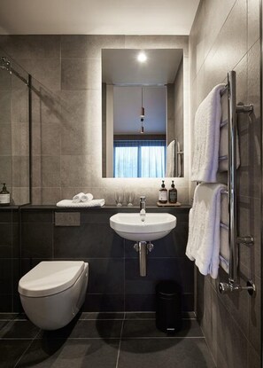 Uma casa de banho moderna com sanita, lavatório e chuveiro.