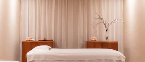 Quarto com duas camas, cabeceiras de madeira e uma janela grande com cortinas leves.