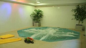 Quarto com um grande elemento aquático no centro, uma planta em vaso e uma toalha amarela no chão.