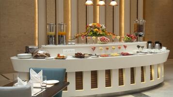 Um buffet de café da manhã com diversos alimentos e um arranjo floral.