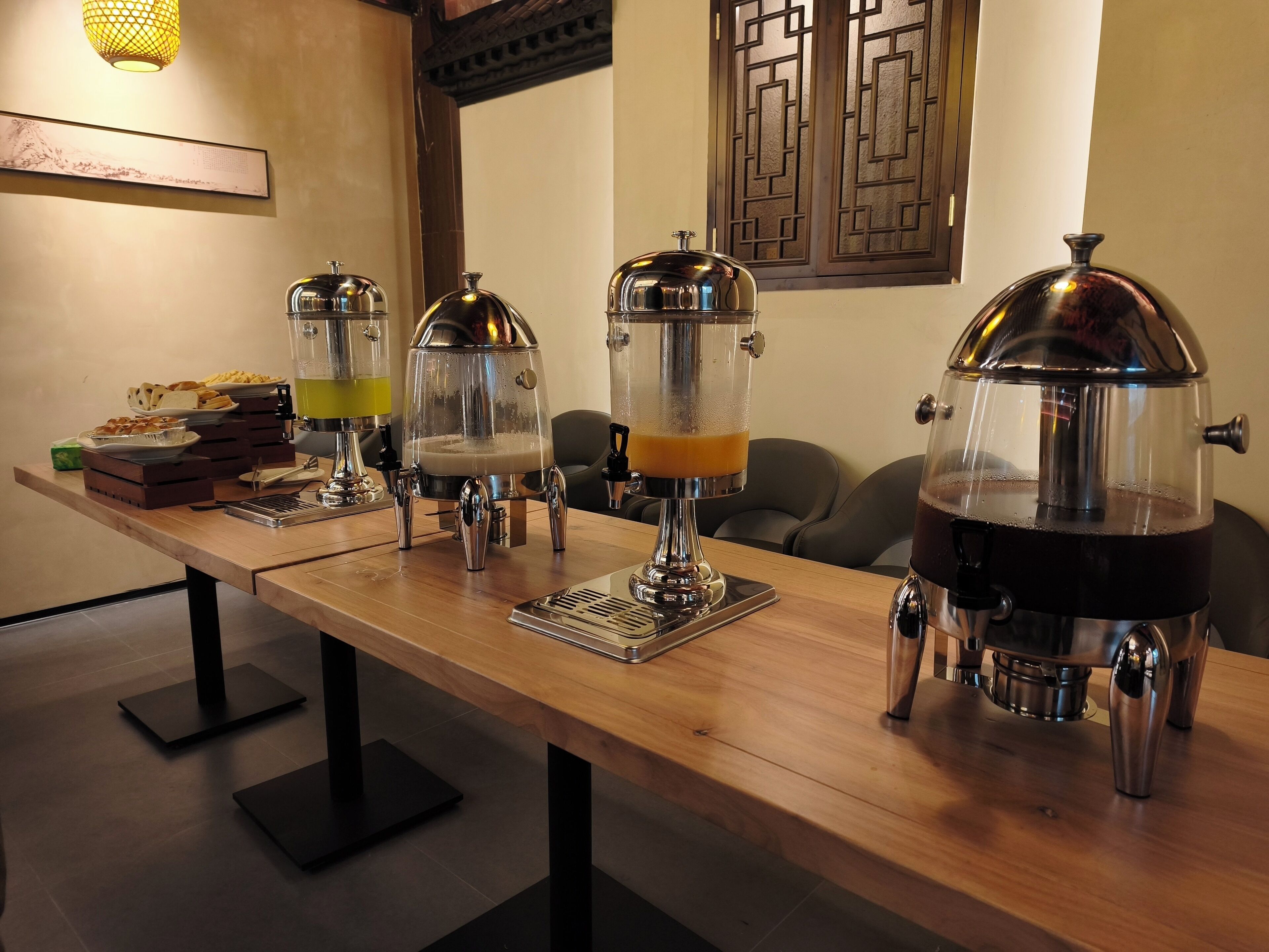 Uma estação de café com quatro máquinas de café, uma mesa de madeira e um painel decorativo na parede.