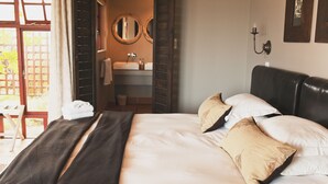 Quarto de hotel com uma cama, banheiro com pia e espelhos, e vista para o exterior.