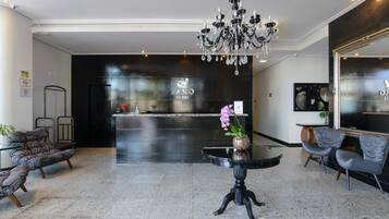 Um hall de hotel com balcão de recepção, um lustre, área de estar e um espelho grande.