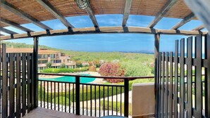 Uma pérgula de madeira com vista para uma piscina e vegetação.