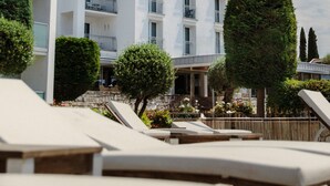 Um hotel de vários andares chamado Portorosé Boutique Hotel, com varandas, área de piscina e paisagismo bem cuidado.