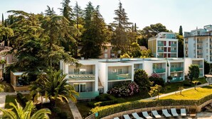 Um hotel moderno com várias varandas, piscina e vegetação exuberante.