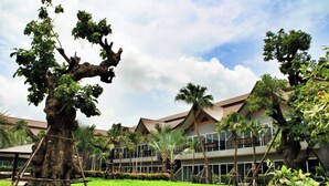 Um resort com edifícios de vários andares, grandes árvores e um gramado bem cuidado.