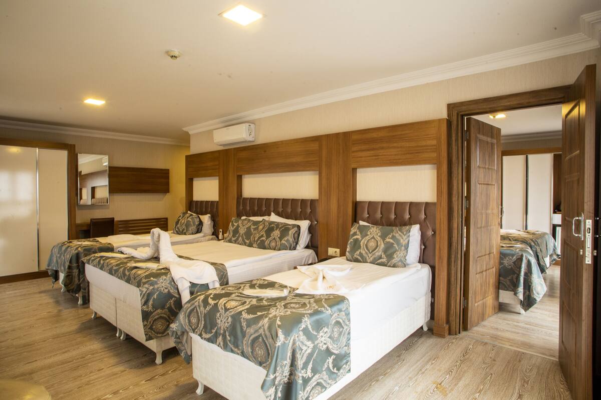 Quarto de hotel com duas camas, cabeceiras de madeira e um espelho grande.