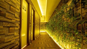 Um corredor com piso de madeira, paredes de pedra e um painel de bambu.