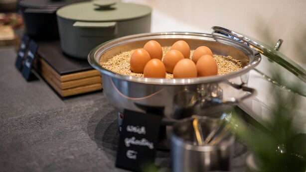 Uma bancada de cozinha com uma tigela de ovos e um recipiente com grãos.