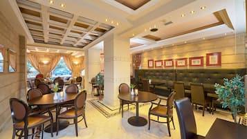 Restaurante com teto alto, lustres e vista para a cidade.