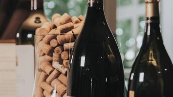 Duas garrafas de vinho sobre uma superfície de madeira, com uma lâmpada ao fundo.