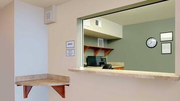 Um espaço de escritório pequeno com uma mesa, um computador e um relógio na parede.