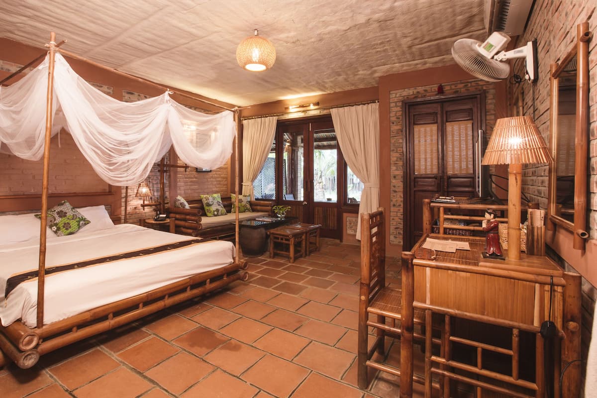 Quarto tradicional com cama de dossel, escrivaninha de madeira e uma cadeira.
