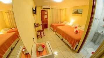 Quarto de hotel com duas camas, uma escrivaninha, uma cadeira e um banheiro.