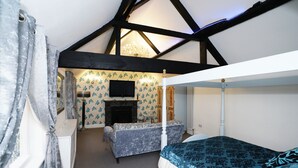Quarto com cama de dossel, um sofá e lareira.