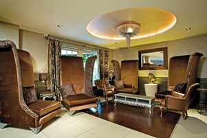 Uma sala de estar luxuosa com poltronas de couro e encosto alto, um sofá e uma mesa de centro.