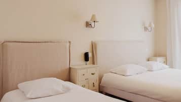 Quarto de hotel com duas camas, uma mesa de cabeceira com abajur, telefone e um pequeno armário.