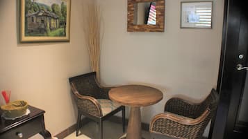 Uma sala de jantar com duas cadeiras de vime, uma mesa redonda de madeira e um quadro na parede.