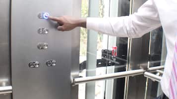 Uma pessoa a operar o painel de comando de um elevador, com visor digital e botões.