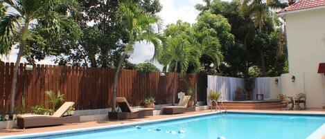 Uma piscina com espreguiçadeiras e um cercado de madeira.