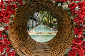 Moldura circular de vime com uma piscina e vista para um edifício ao fundo.
