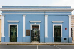 Um edifício azul com três portas, cada uma com um pilar branco e um letreiro sobre a porta central.