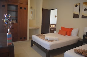 Quarto com uma cama, mesa de cabeceira, cômoda e espelho.