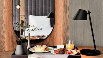 Disposição para o café da manhã com pratos de comida, uma xícara de café, um vaso com plantas e uma luminária de cabeceira.