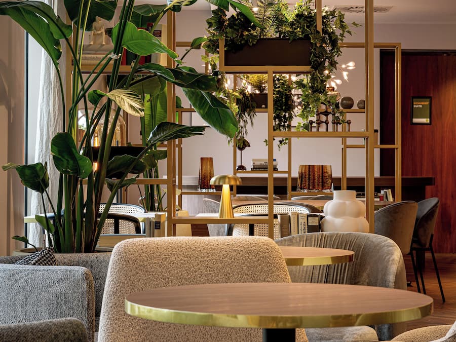 Um interior moderno com uma mesa redonda, cadeiras e diversas plantas.