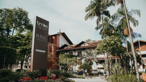 Entrada moderna de hotel com placa indicando 'Timbo Park Hotel' e 'D.O.C. Restaurante'.