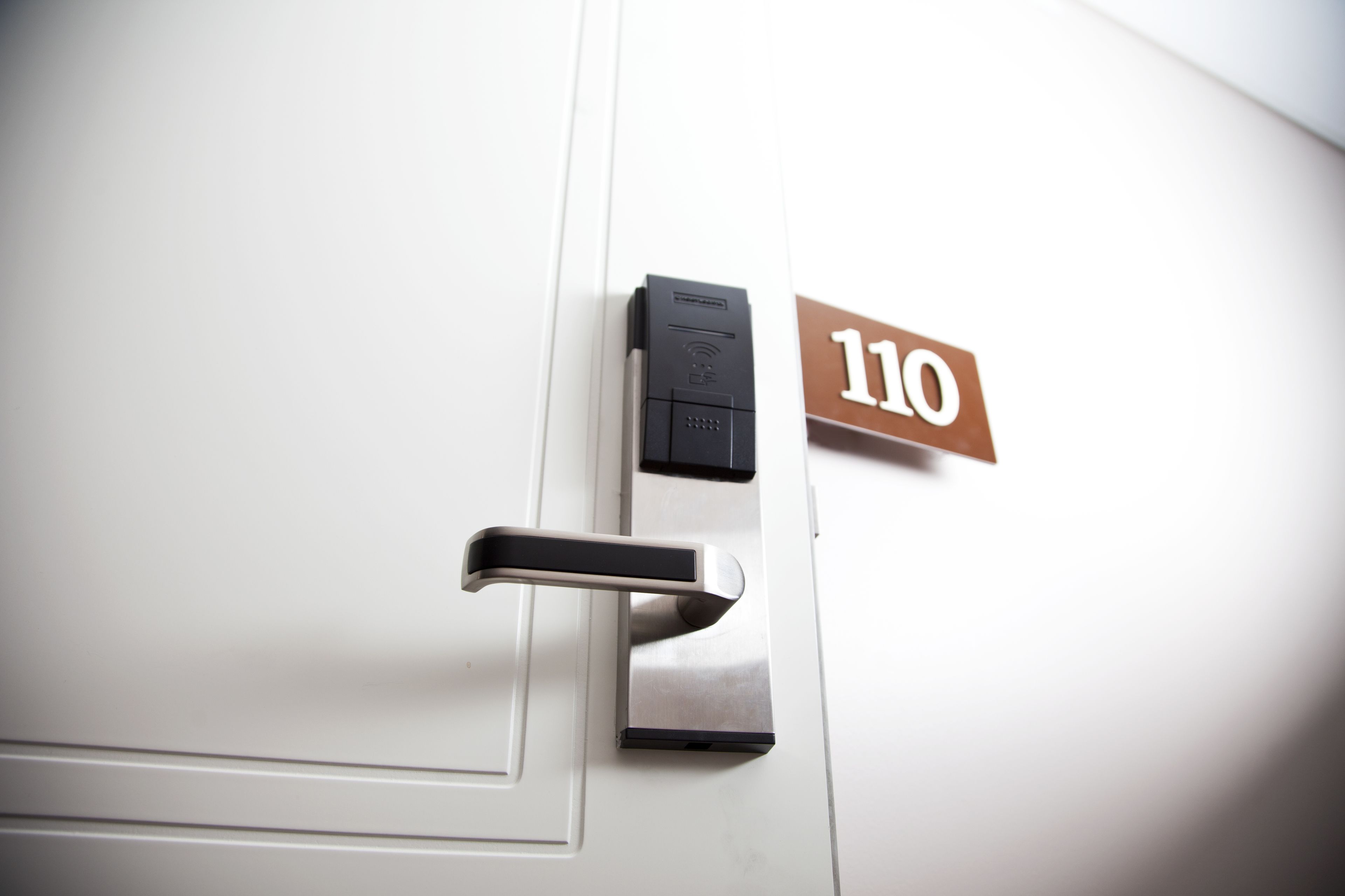 Uma porta com placa numérica '110' e uma maçaneta moderna.